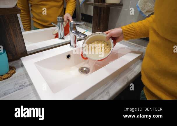 Wash oat grains under the water tap. Cooking food oatmeal, in the ...