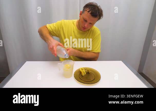 A man squeezes juice from a lemon, adding natural lemon juice to ...