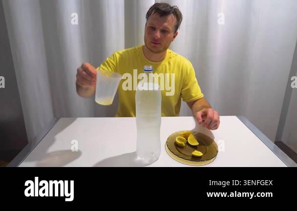 A man squeezes juice from a lemon, adding natural lemon juice to ...
