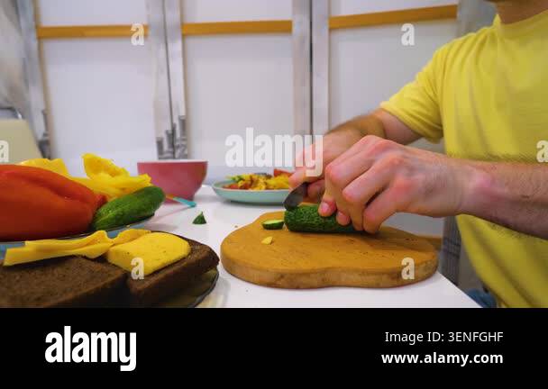 Slicing a ripe fresh cucumber on the board at dinner in the kitchen, a ...