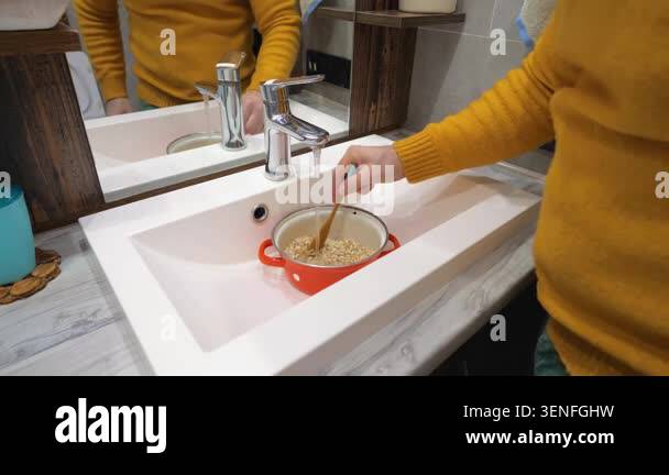Wash oat grains under the water tap. Cooking food oatmeal, in the ...