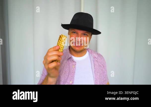 Holding a wafer roll with condensed milk in his hands, a stylish man in ...