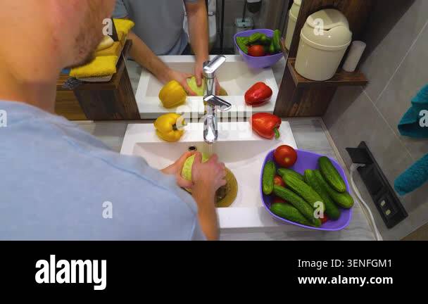 A man washes white cabbage under the water tap in the kitchen. Slow ...
