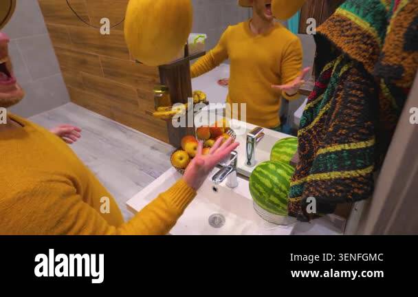 A young man washes a melon under the water tap, juicy apples in the ...