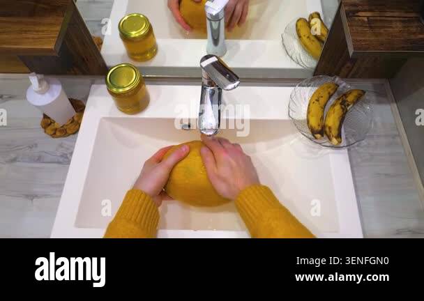 Wash melon under the water tap, top view. Male hands wash melon fruit ...