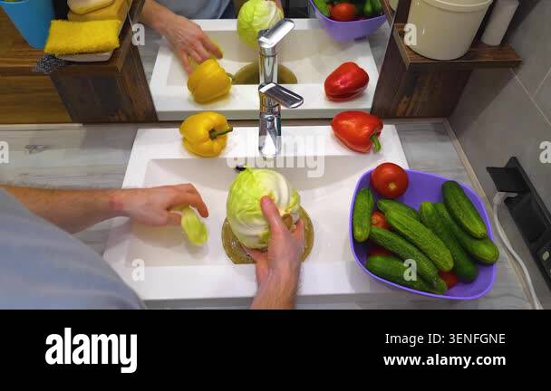 A man washes white cabbage under the water tap in the kitchen. Slow ...