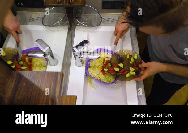 A man cuts greens, chopped cabbage. Prepare the salad, wash it under ...