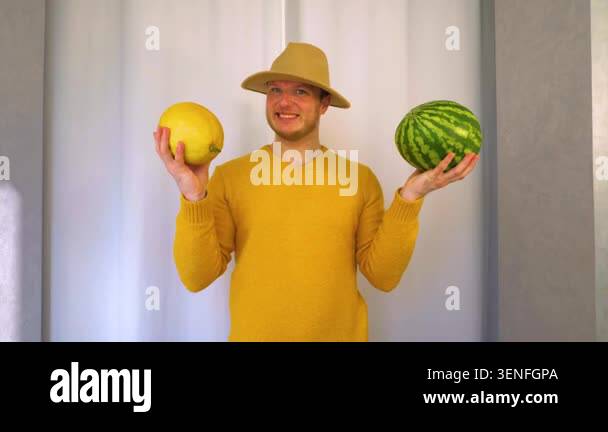 A man in bright clothes with a fruit melon and watermelon in his hands ...