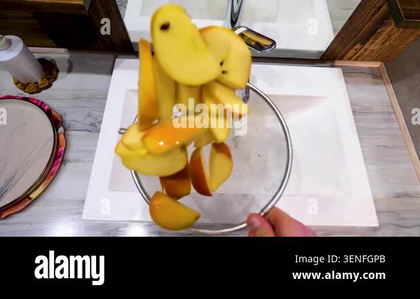A man washes sliced apples under the water tap in the kitchen. Wash the ...