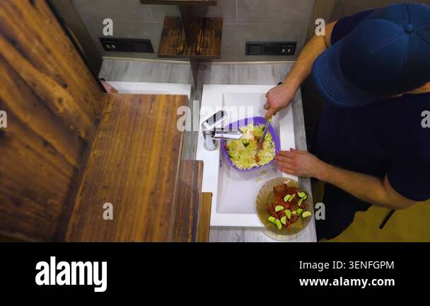 A man cuts greens, chopped cabbage. Prepare the salad, wash it under ...