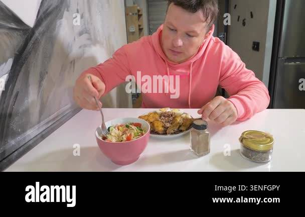 A man is having dinner, buckwheat with chicken wings, with salad in a ...
