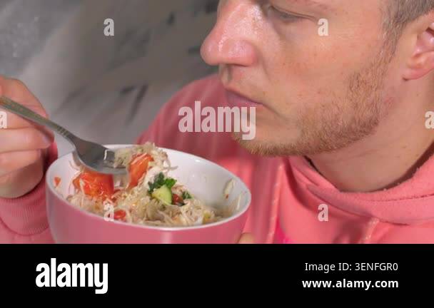 A man eats dinner with a fork, a salad of fresh herbs, diet food ...