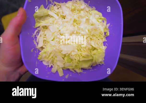 A man prepares a vegetable salad, chopped white cabbage in a salad ...