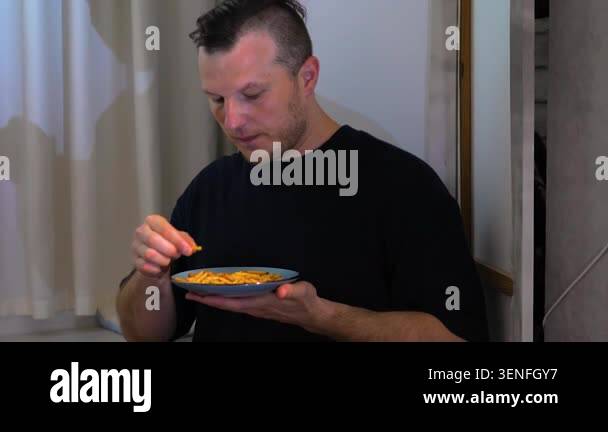 A young man eats French fries from a plate. Male eat fast food fried ...