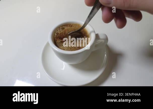 Stirring coffee with a spoon. A man's hand stirring coffee in a cup ...