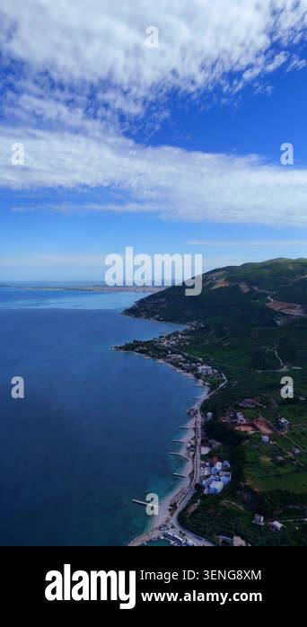 Drone flying high along a scenic coastline with mountains, piers and ...