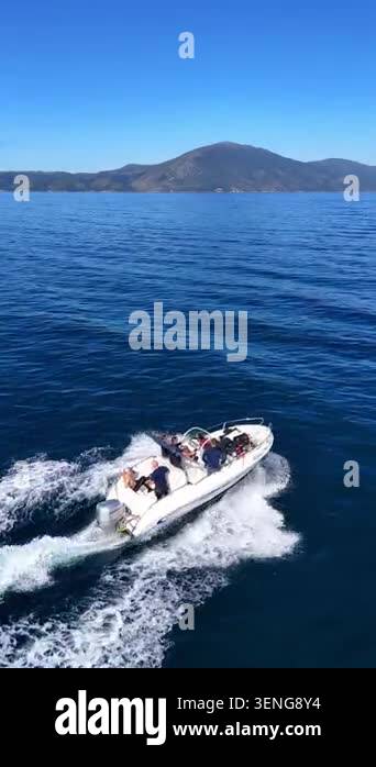 Drone tracking a speedboat cruising through calm open sea along an ...