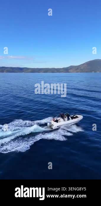 People on a speedboat heading into the open sea while a stationary ...