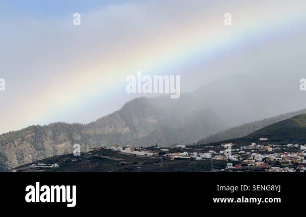 Rainbow forming above mountain village scenic hopeful natural moment ...