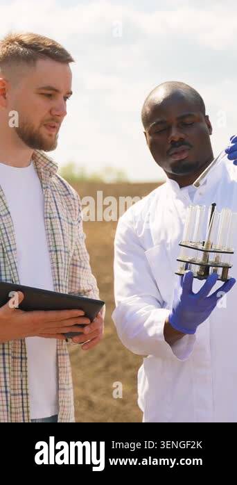 Agronomist and a farmer analyzing soil samples in test tubes. The ...