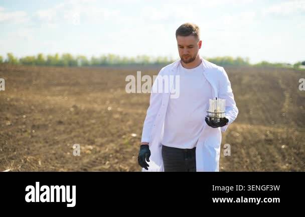 Agricultural scientist wearing a lab coat and gloves walking through a ...