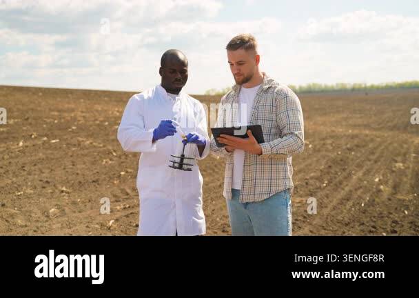 African american scientist in a white coat showing soil samples in test ...