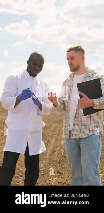 Agronomist scientist in a lab coat is taking a soil sample and showing ...