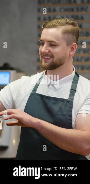 Young male barista wearing an apron skillfully preparing a delicious ...