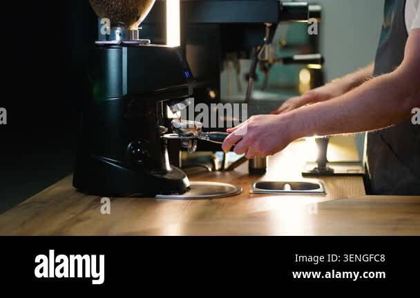 Unrecognizable barista using a professional grinder to fill a ...