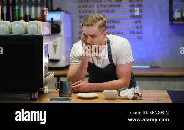 Overworked young barista feeling tired and sleepy at the coffee shop ...