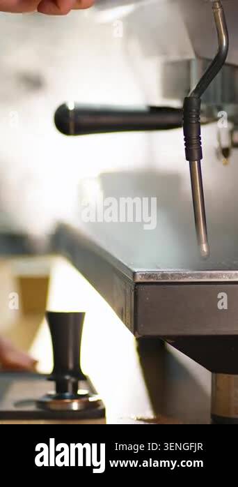 Close up of a barista tamping fresh coffee grounds with a tamper and ...
