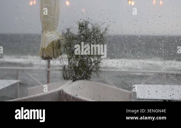 View of the sea from a coastal restaurant in stormy weather with rain ...