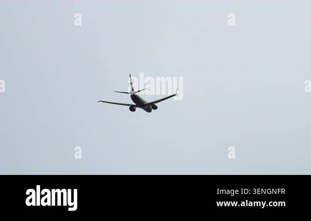 A commercial narrow body jet seen from below flying through a pale ...