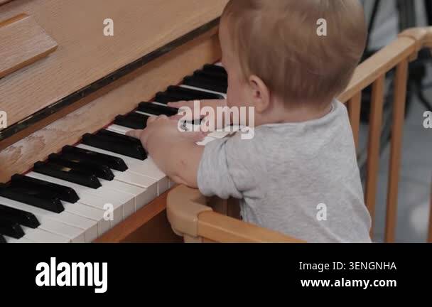 Toddler engaged with wooden piano keys attentively. Little one ...
