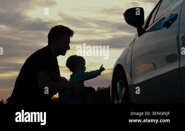 Baby and loving parent connect charging cable into an electric car ...