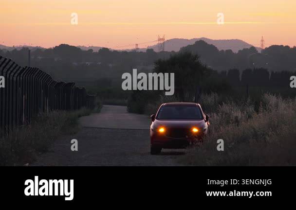 Red SUV stands parked on a quiet rural road at dusk with hazard lights ...