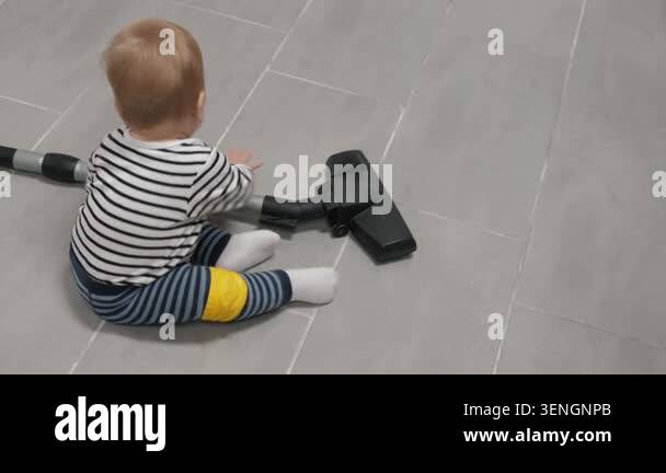 Toddler explores cleaning device joyfully. Young child investigates ...