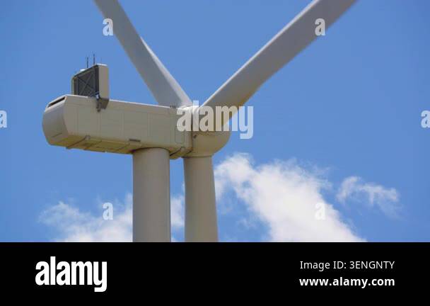 Low angle close view of a wind turbine nacelle and spinning blades set ...