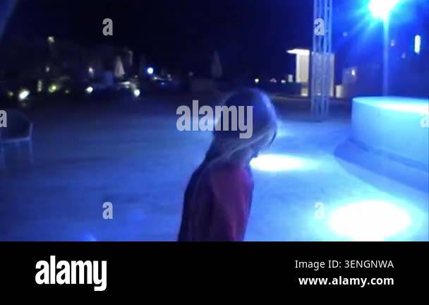 A young girl in Egypt dances on a wide tiled dance floor washed in blue ...