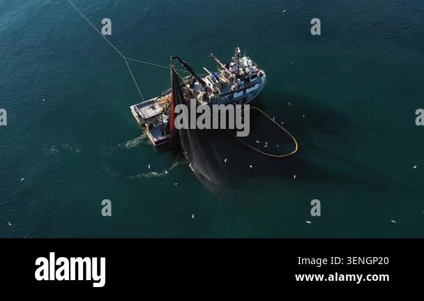 A bird's eye footage of a large fishing vessel retrieving its nets ...