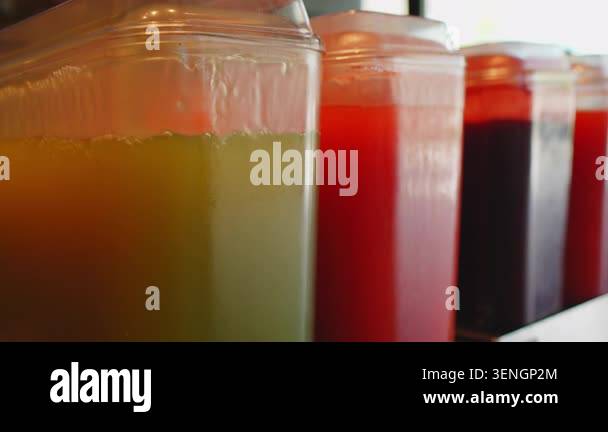 Close-up of a row of glass dispensers filled with colorful fresh juices ...