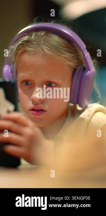Close up of a young girl wearing purple headphones, watching a tablet ...