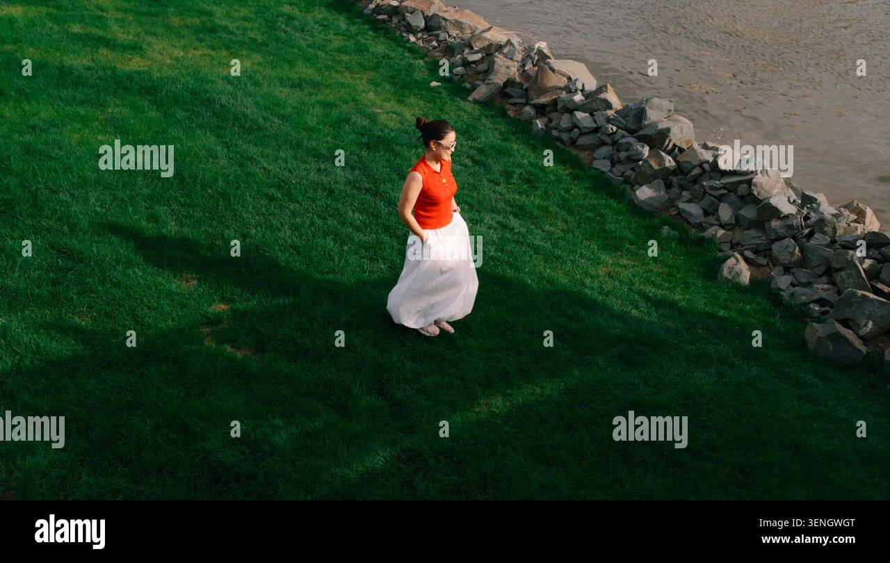 Woman in red top spinning on green grass near river aerial view Stock ...