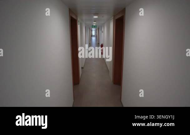 Empty narrow corridor in a modern building lined with wooden doors ...