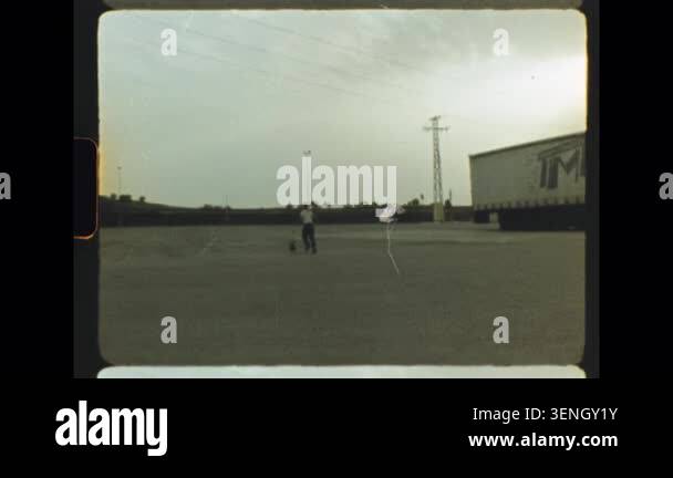 Young child girl runs across a wide empty parking lot with a small ...