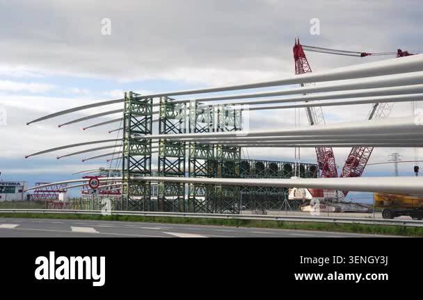 Several enormous white wind turbine blades resting on tall green steel ...