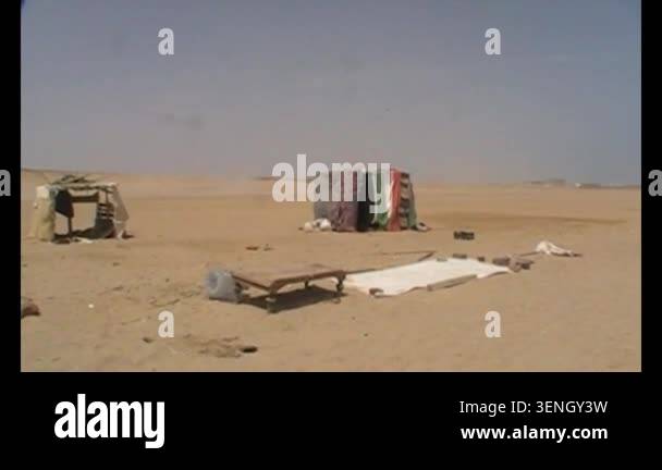 Wide view of a remote desert camp with makeshift cloth shelters a ...