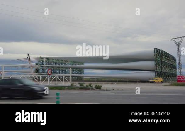 Long white wind turbine blades resting on green steel racks near a ...