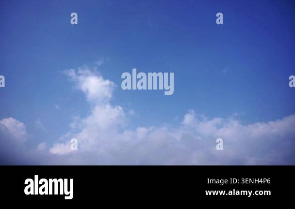 Time-lapse video of white clouds moving fast across a bright blue sky ...