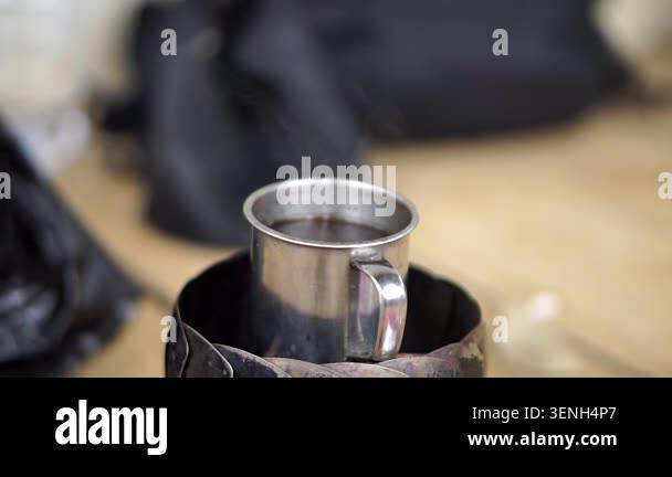 Top view of frothy coffee being cooked in a metal mug on a portable gas ...